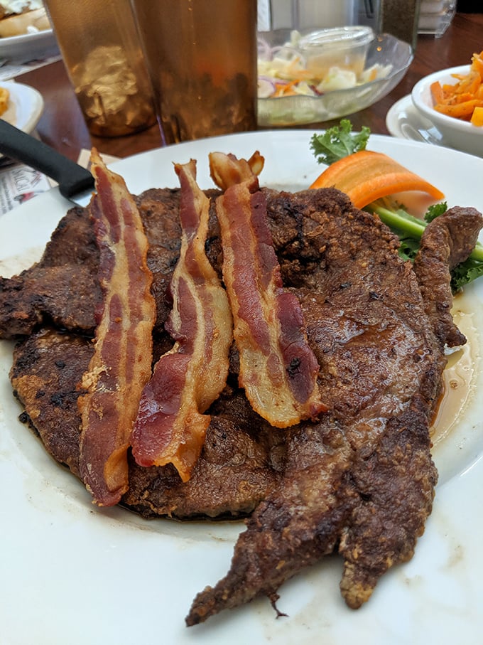 This steak topped with bacon strips isn't just a meal – it's a declaration that today is not the day you're counting calories.