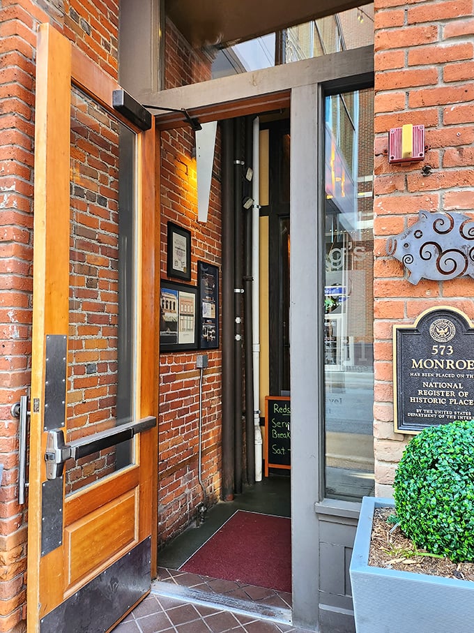 The entrance to meat paradise – where that historic brick exterior gives way to the promise of smoky delights that await just beyond those wooden doors.