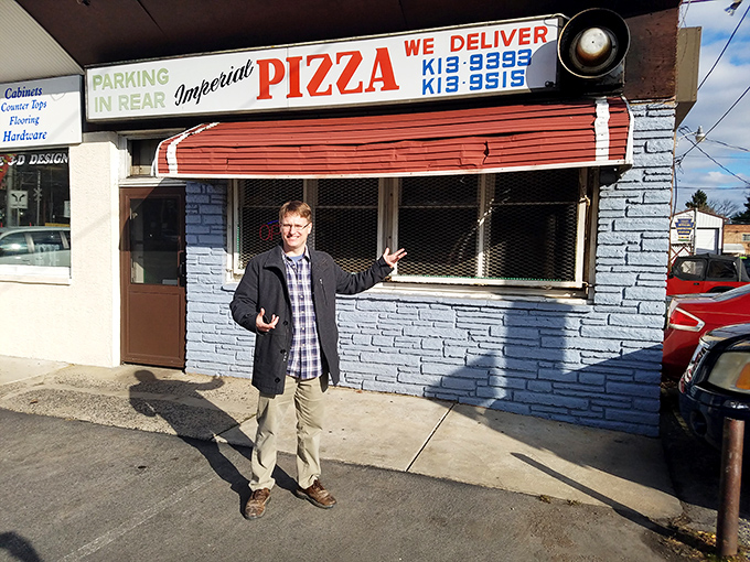 The universal gesture of pizza enthusiasm outside Imperial's blue facade. Some places just inspire spontaneous joy.