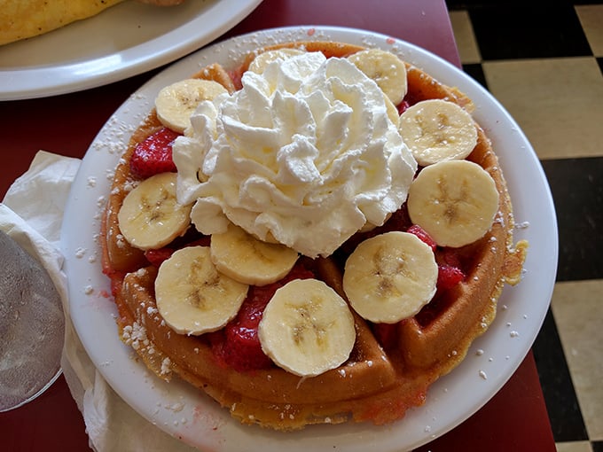 This waffle topped with fresh fruit and whipped cream isn't just breakfast—it's dessert with permission to eat it before noon.
