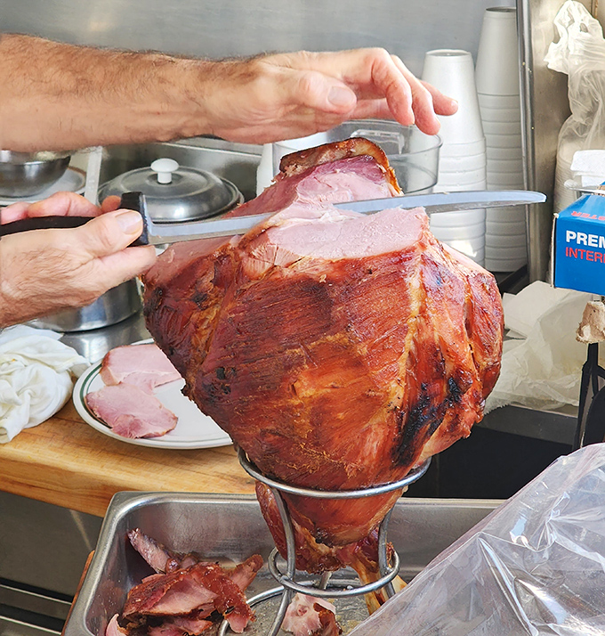 The whole ham in all its glory, being carved with surgical precision. This glistening masterpiece is the cornerstone of Mike's enduring legacy.