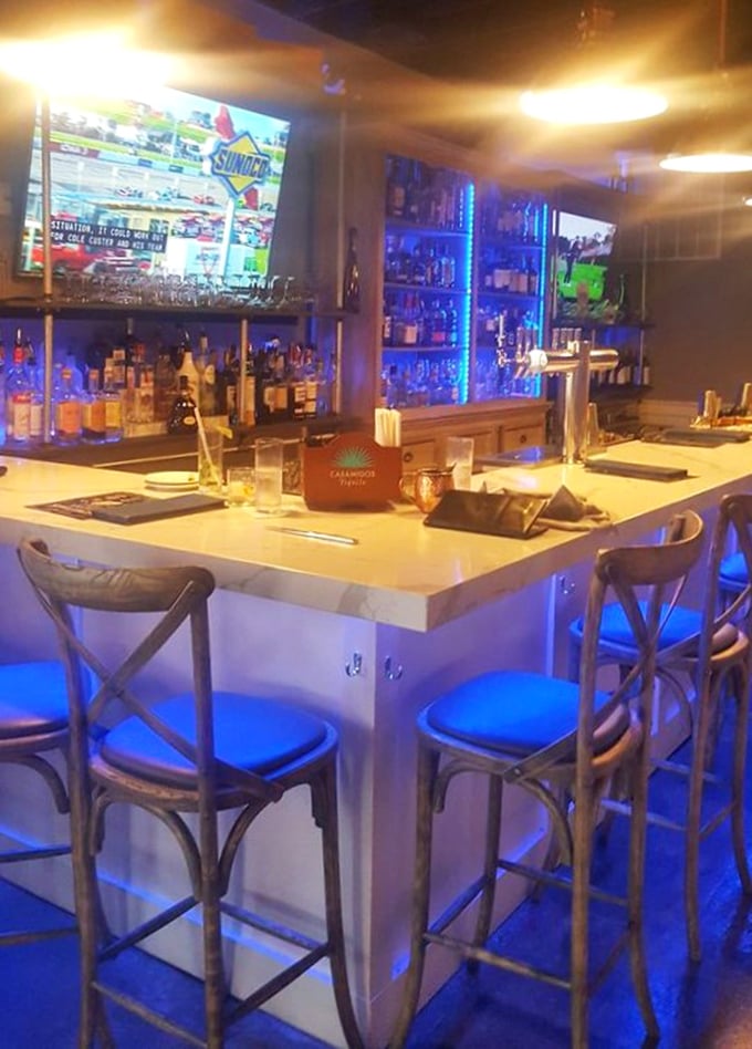 The bar glows with blue promise—where sports on TV and premium spirits create that perfect "one more before we go" atmosphere.