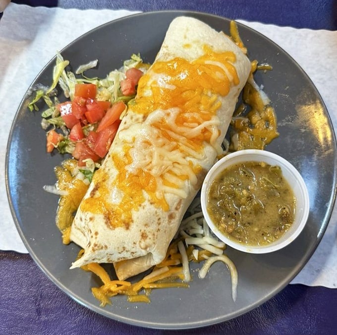 A breakfast burrito so perfectly constructed it deserves its own architectural award—with green chile sauce standing in for the ribbon-cutting ceremony.
