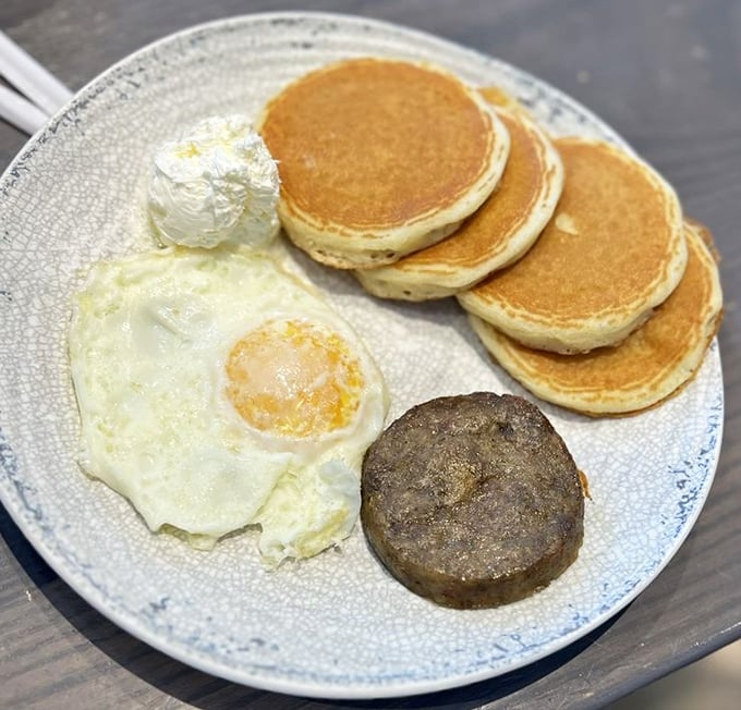 The classic breakfast plate – golden pancakes, perfectly fried egg, and sausage – proves sometimes the simplest combinations are the most satisfying.