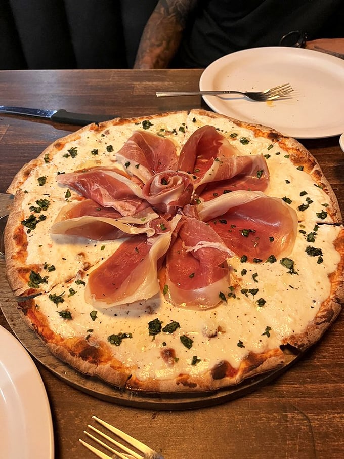 Prosciutto arranged like a delicate rose atop a white pizza—proof that Italians understood food as art long before Instagram.