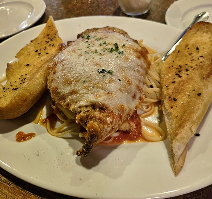 Chicken Parmigiana that doesn't mess around—golden-crusted, cheese-blanketed, and flanked by garlic bread sentinels ready to soak up every last bit of sauce.