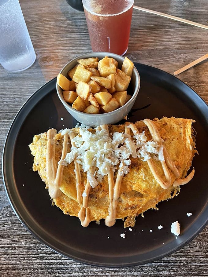 An omelet that's had a spa treatment—draped in sauce, sprinkled with cheese, and served with potatoes that gleam like little golden nuggets.