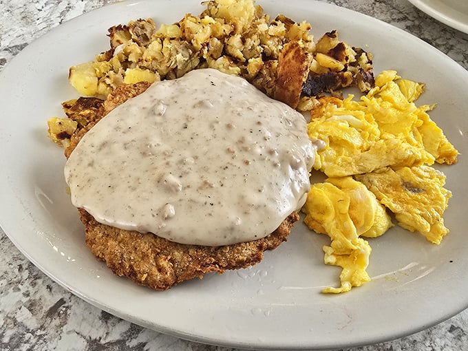 Country fried steak smothered in pepper gravy—the kind of breakfast that makes you want to buy a farm just to work it off.