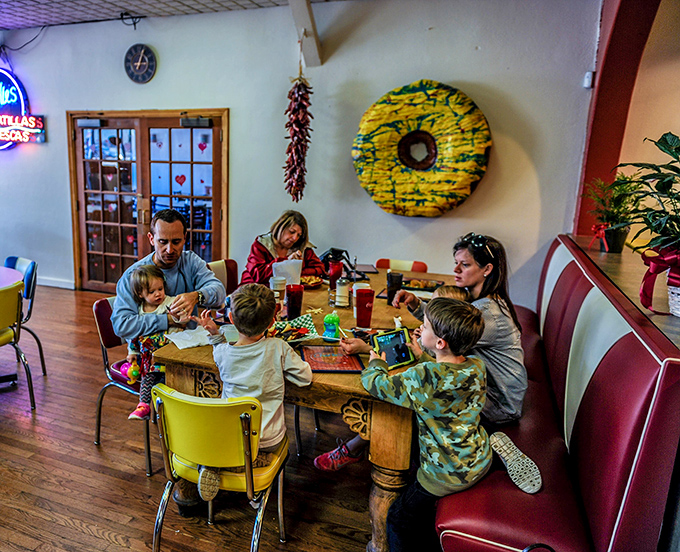 Families gather around mismatched tables because great food brings people together regardless of matching furniture or formal settings.