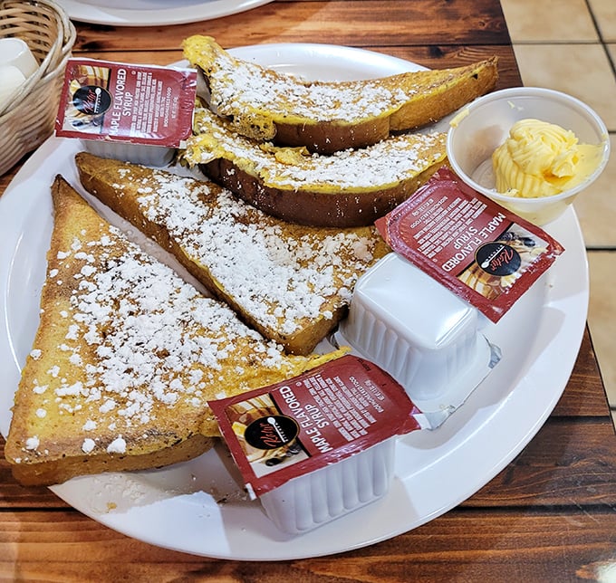 French toast dusted with powdered sugar and served with real butter—breakfast's answer to dessert. The packets of syrup are just waiting to complete this sweet symphony.