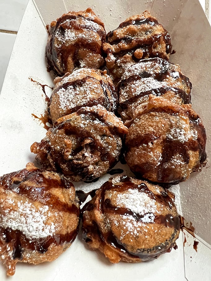 Deep-fried Oreos dusted with powdered sugar and drizzled with chocolate—proof that dessert can be both ridiculous and ridiculously good.