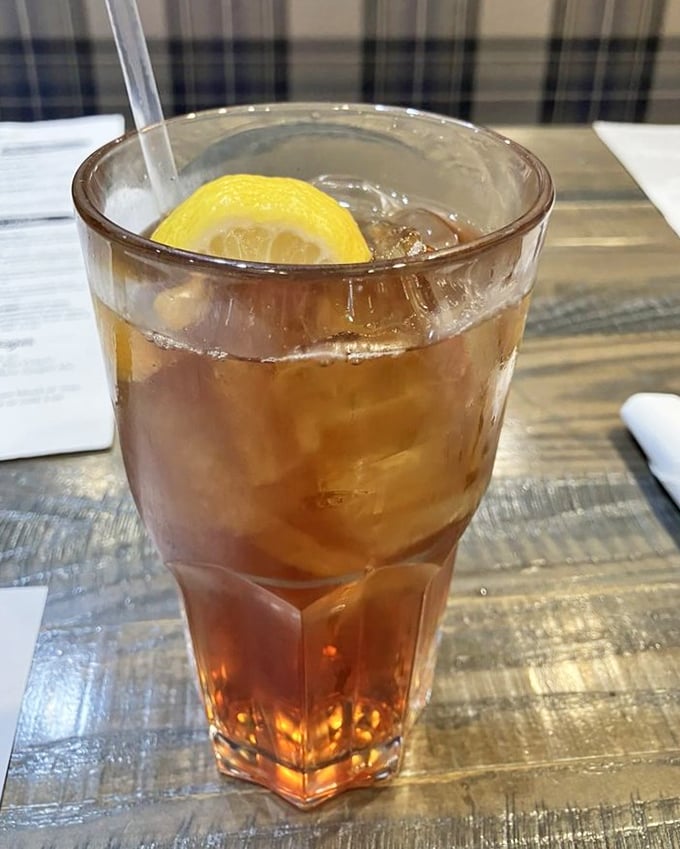 A tall glass of amber iced tea with lemon—simple, refreshing, and the perfect companion to whatever deliciousness you've ordered.