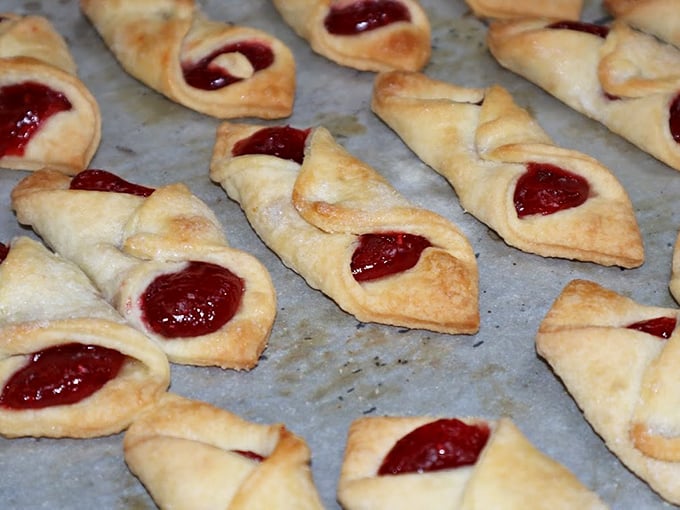 These jam-filled kolaczki cookies fold around their ruby centers like they're hugging the fruit filling they know you'll soon be enjoying.