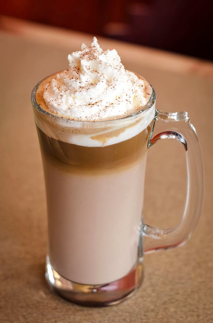 This layered latte isn't just coffee—it's a morning hug in a mug, topped with a cloud of whipped cream dusted with cinnamon.