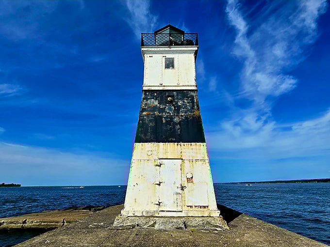 The lighthouse wears its weathered stripes proudly, a beacon that's seen more storms than your local meteorologist.