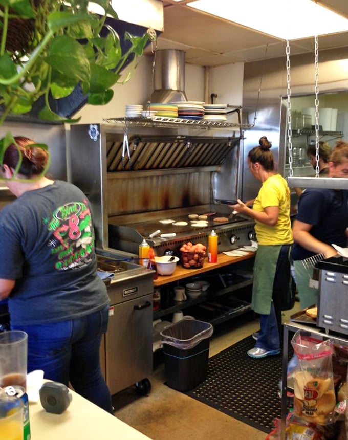 The open kitchen reveals the choreographed dance of breakfast preparation—pancakes hitting the griddle as eggs sizzle nearby.