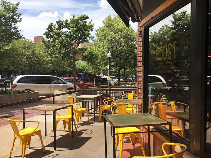 Those cheerful yellow chairs on the patio aren't just seats—they're front-row tickets to Lawrence's vibrant street life and post-breakfast people-watching. 
