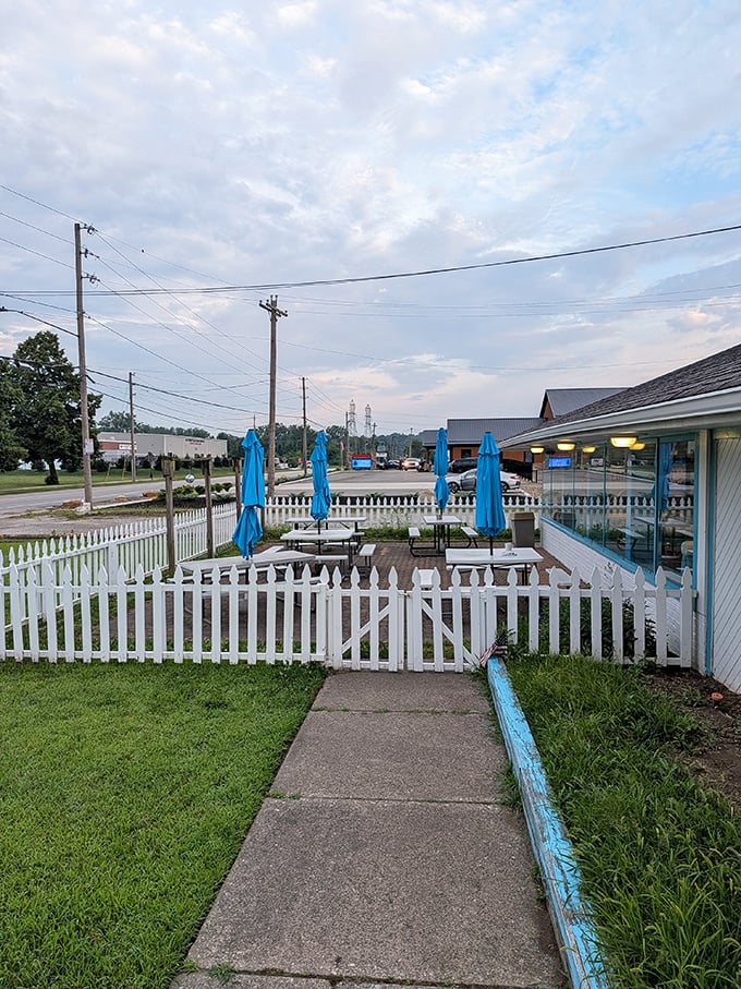 The outdoor patio, surrounded by white picket fence and blue umbrellas, where summer breakfasts taste even better with a side of fresh air.