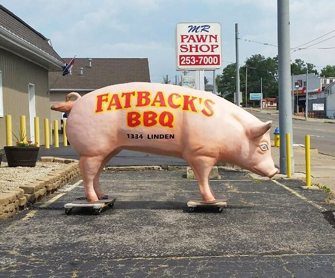 This pink pig mascot doesn't run from its destiny—instead, it proudly advertises the address where pork reaches its highest calling.