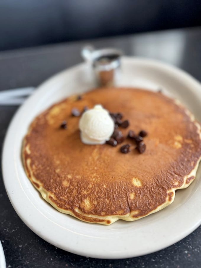 A pancake so perfectly golden it deserves its own sunrise soundtrack—topped with a melting pat of butter and chocolate chips for good measure.
