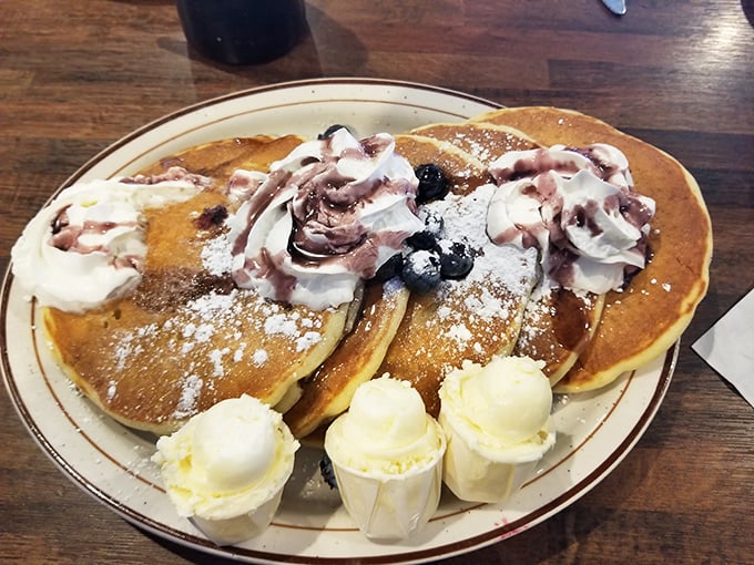 Pancakes that don't just arrive – they make an entrance, dressed in whipped cream and berries like they're heading to prom.
