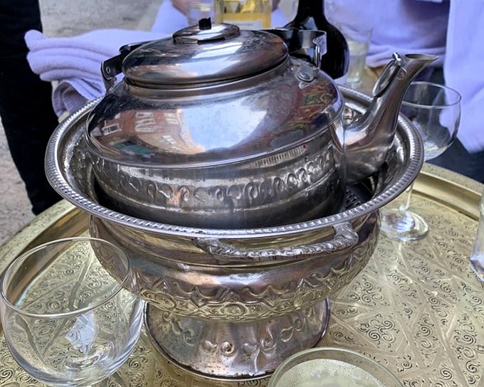 The ceremonial pouring of mint tea from ornate silver pots isn't just showmanship—it's the traditional method that aerates the sweet brew to perfection.