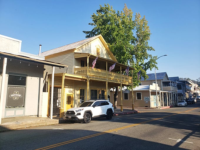 American flags flutter above a perfectly preserved Gold Rush-era building, now home to shops where you can spend modern currency instead of gold nuggets.