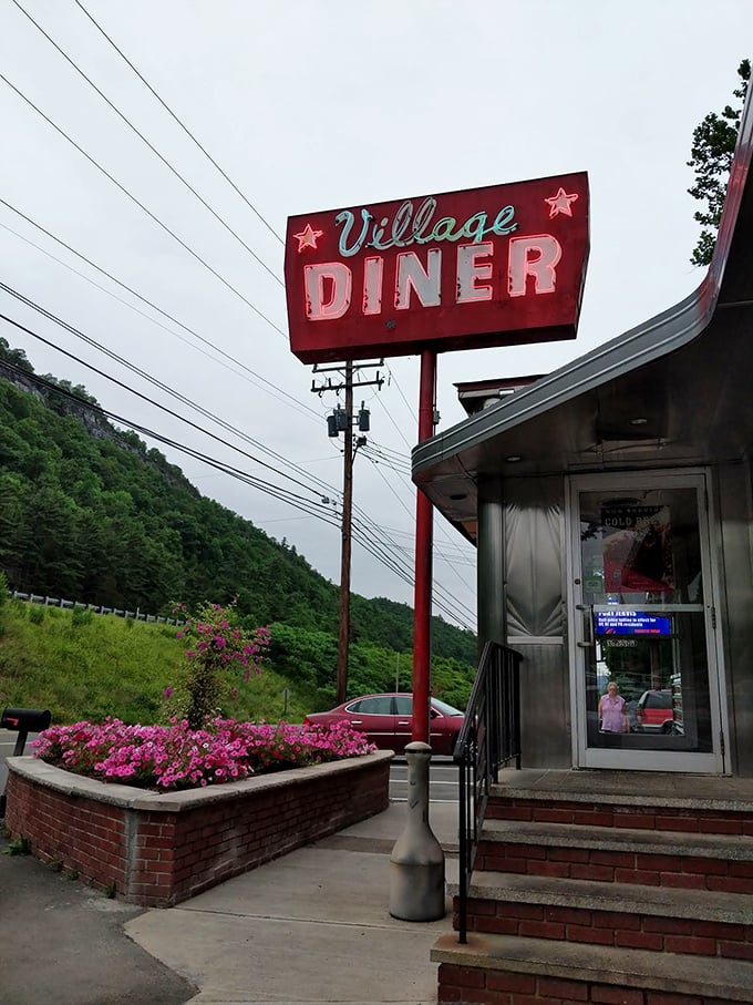 That iconic Village Diner sign against Pennsylvania's rolling hills – a promise of culinary comfort that's visible from down the road.