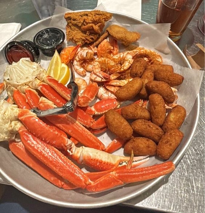 Snow crab legs, peel-and-eat shrimp, and hush puppies create a seafood symphony on a metal platter. This isn't just dinner—it's an event.