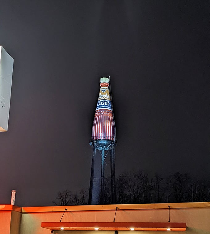 By night, the illuminated bottle glows against the darkness, a beacon for road-trippers and proof that the best attractions shine at any hour.
