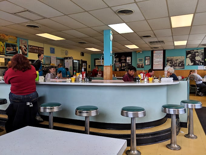 The counter—where solo diners find community, regulars claim their territory, and waitresses perform the ballet of coffee pot refills with practiced grace.
