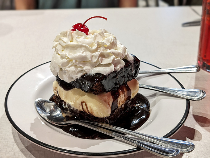 A brownie sundae that makes time stop – hot fudge cascading down vanilla ice cream like chocolate lava, crowned with clouds of whipped cream.