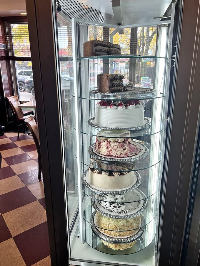 The rotating cake display—a glass tower of temptation where willpower goes to die and "I'll just have a bite" becomes a beautiful lie.