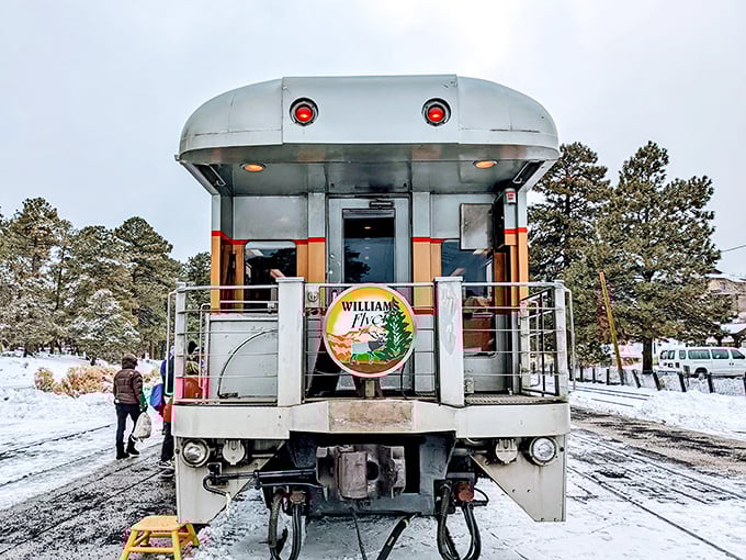 The Williams Flyer observation car stands ready for boarding in winter wonderland conditions. Those red taillights have guided travelers home through decades of Arizona nights.