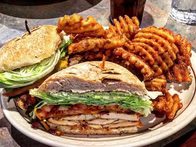 The club sandwich: architectural marvel of the diner world. Layers of flavor skewered together, accompanied by waffle fries that could make a potato proud.