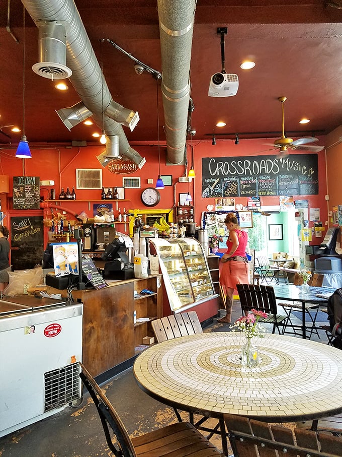 Behind the counter where coffee magic happens—exposed pipes overhead and pastries below create the perfect backdrop for your morning caffeine transaction.