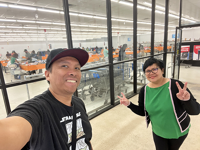 Happy shoppers flashing victory signs—the universal gesture that says "We conquered the bins and our wallets survived to tell the tale."