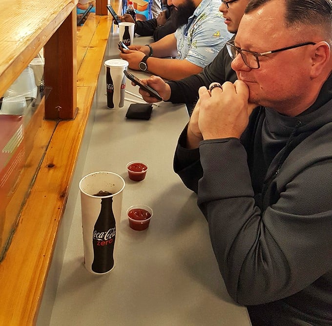 The universal posture of anticipation—hunched slightly forward, focused entirely on the imminent arrival of sandwich perfection.