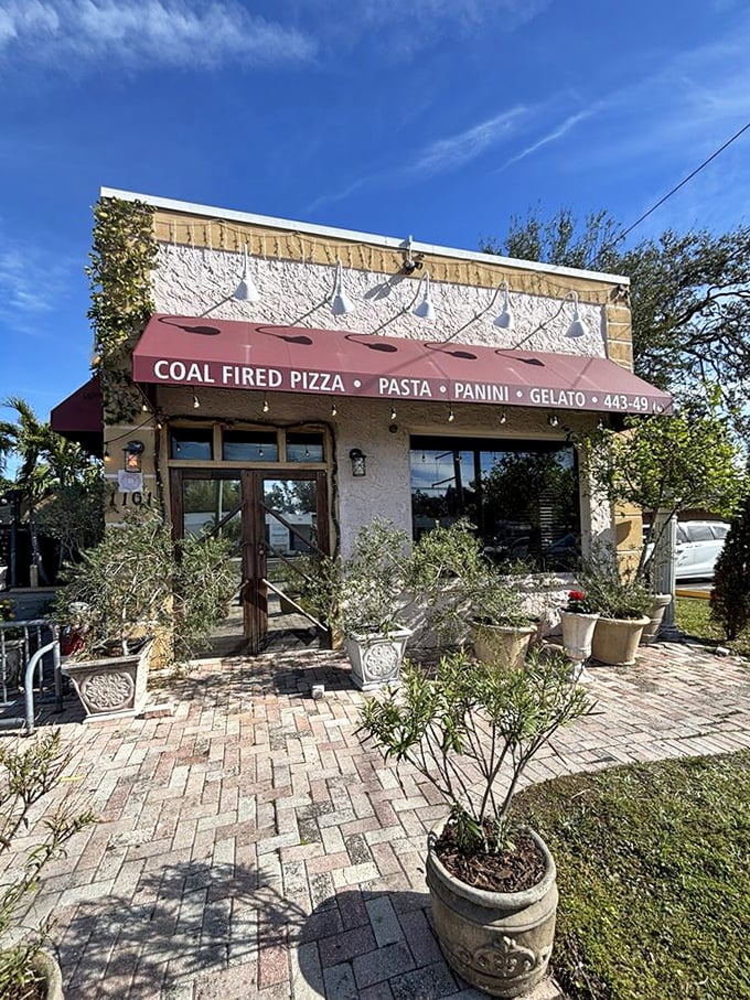 The entrance, with its Mediterranean-inspired planters and brick pavers, sets the stage for the culinary journey that awaits inside.