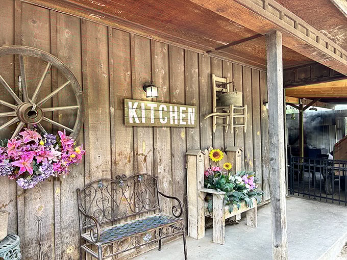 The porch welcomes weary travelers with country charm – wagon wheel, wrought-iron bench, and flowers that seem to say, "Slow down, you're home now." 