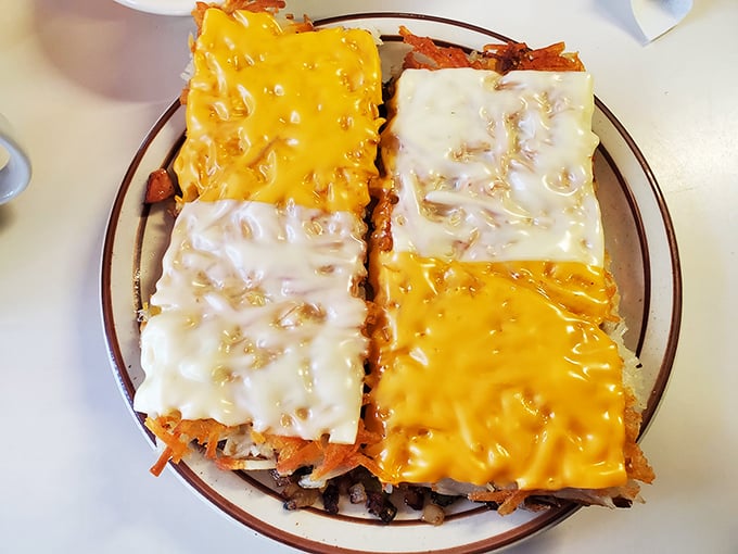 Hashbrowns wearing their cheese proudly—a patchwork quilt of yellow and white dairy goodness atop crispy potatoes. Breakfast architecture at its finest.