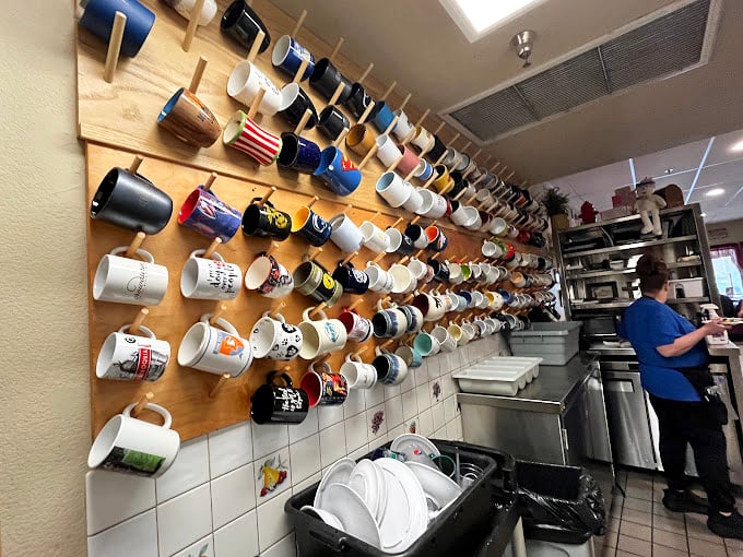 The wall of coffee mugs tells the story better than words could – this is a place where regulars leave a piece of themselves, one ceramic handle at a time.