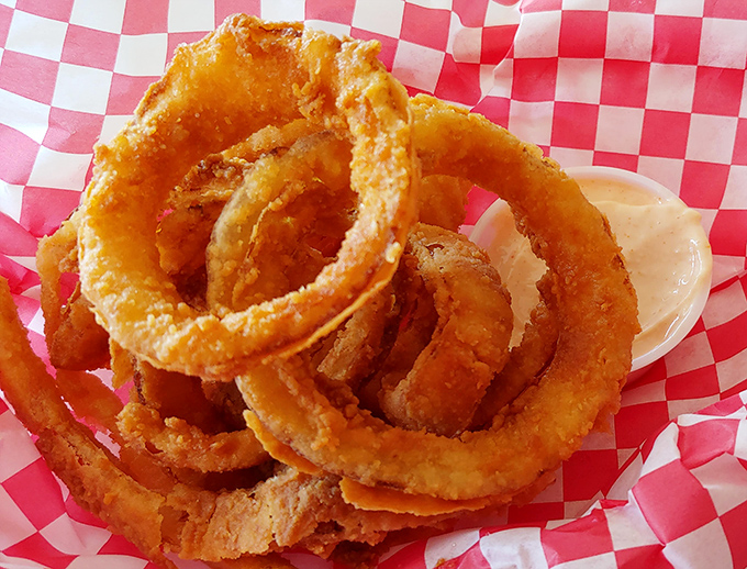 Golden onion rings stacked like delicious jewelry, each one a perfect circle of crispy-on-the-outside, tender-on-the-inside satisfaction.