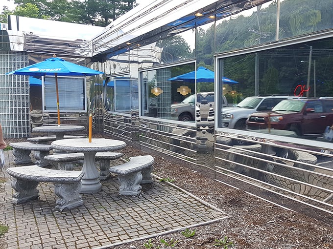 The outdoor patio offers stone tables under blue umbrellas – a civilized option for those who prefer their comfort food with a side of fresh mountain air.