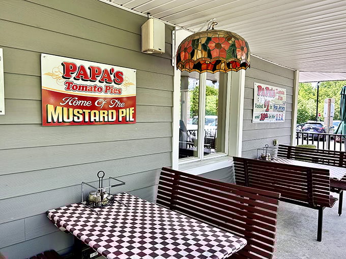 Outdoor seating with a side of history. That sign proudly proclaiming "Home Of The MUSTARD PIE" is both a statement and a challenge to pizza traditionalists.