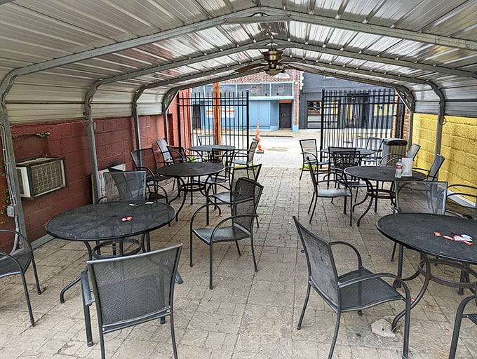 The covered patio offers a moment of respite, where metal tables and chairs await the next round of satisfied customers.