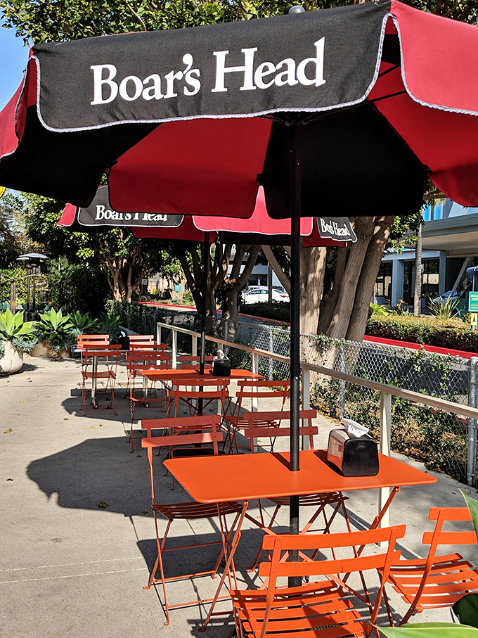 The outdoor seating area under Boar's Head umbrellas—where Los Angeles sunshine meets sandwich perfection in urban harmony.