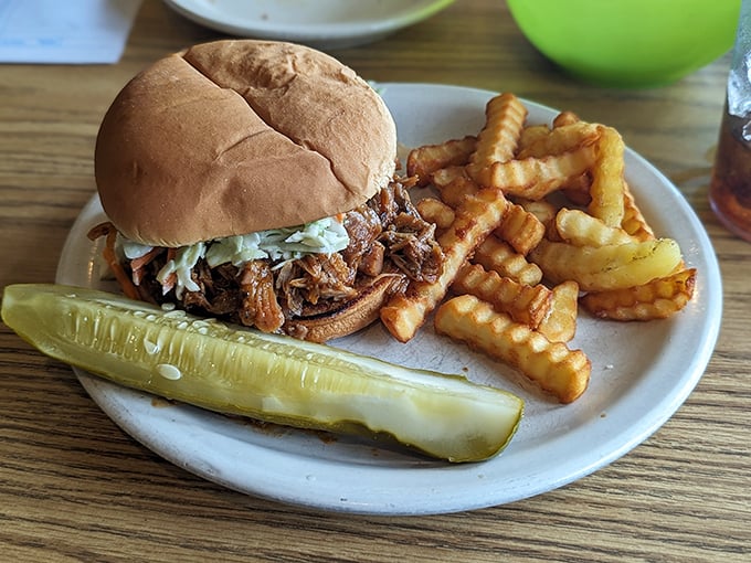 A pulled pork sandwich with crispy crinkle-cut fries and a pickle spear—simple pleasures that remind you why classics never go out of style.
