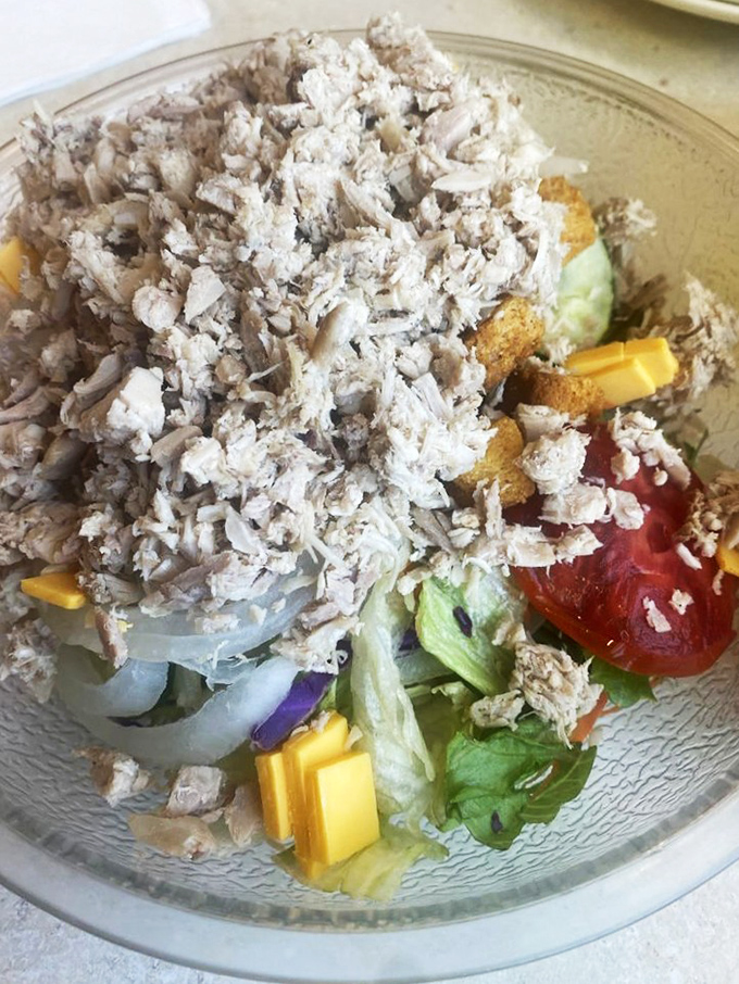 This isn't just a salad; it's a small mountain of turkey atop a garden, where cheese cubes play hide and seek with croutons.
