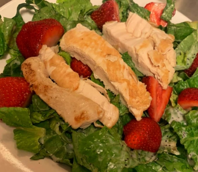 A salad that proves healthy eating doesn't have to be punishment—fresh greens, strawberries, and chicken that wasn't sad about its life choices.